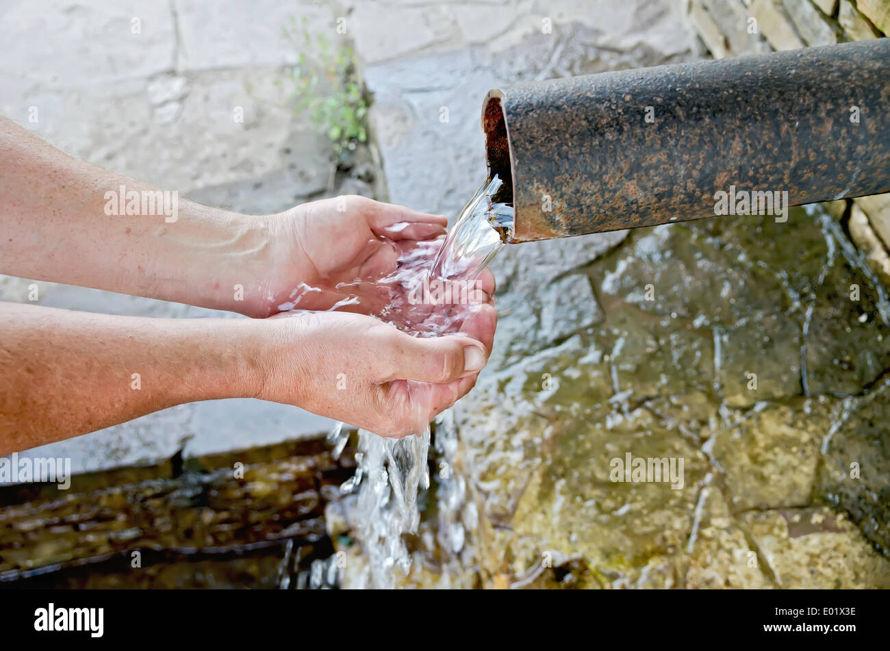 Spring water flows from the pipe into the hands of the men on the ...