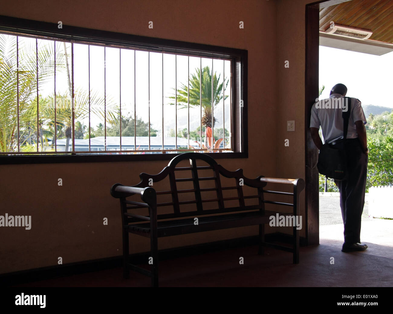 a man standing leans against a wall waiting for a taxi in the Caribbean ...