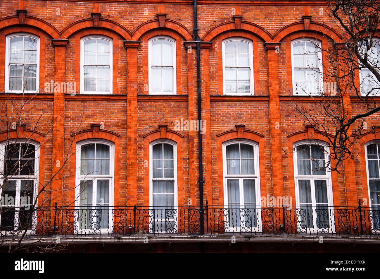 facade of a red brick house with white windows Stock Photo - Alamy