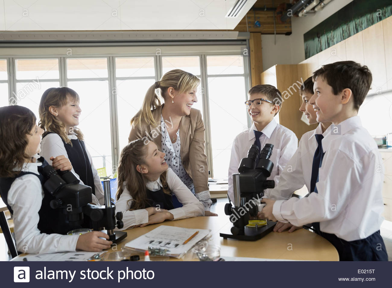 Elementary students and teacher using microscopes in classroom Stock ...