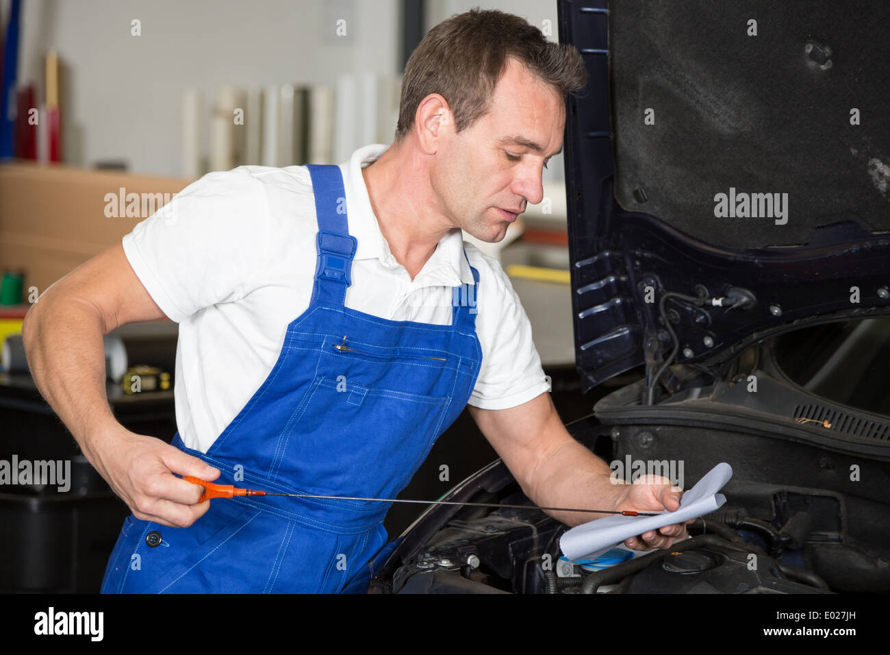Mechanic checking oil level at a car in garage Stock Photo - Alamy