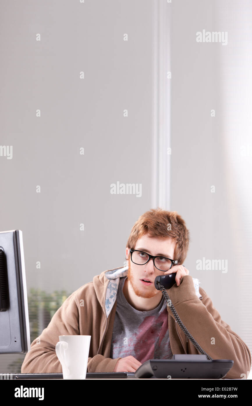 Young redheaded office worker listening to an annoying and boring ...