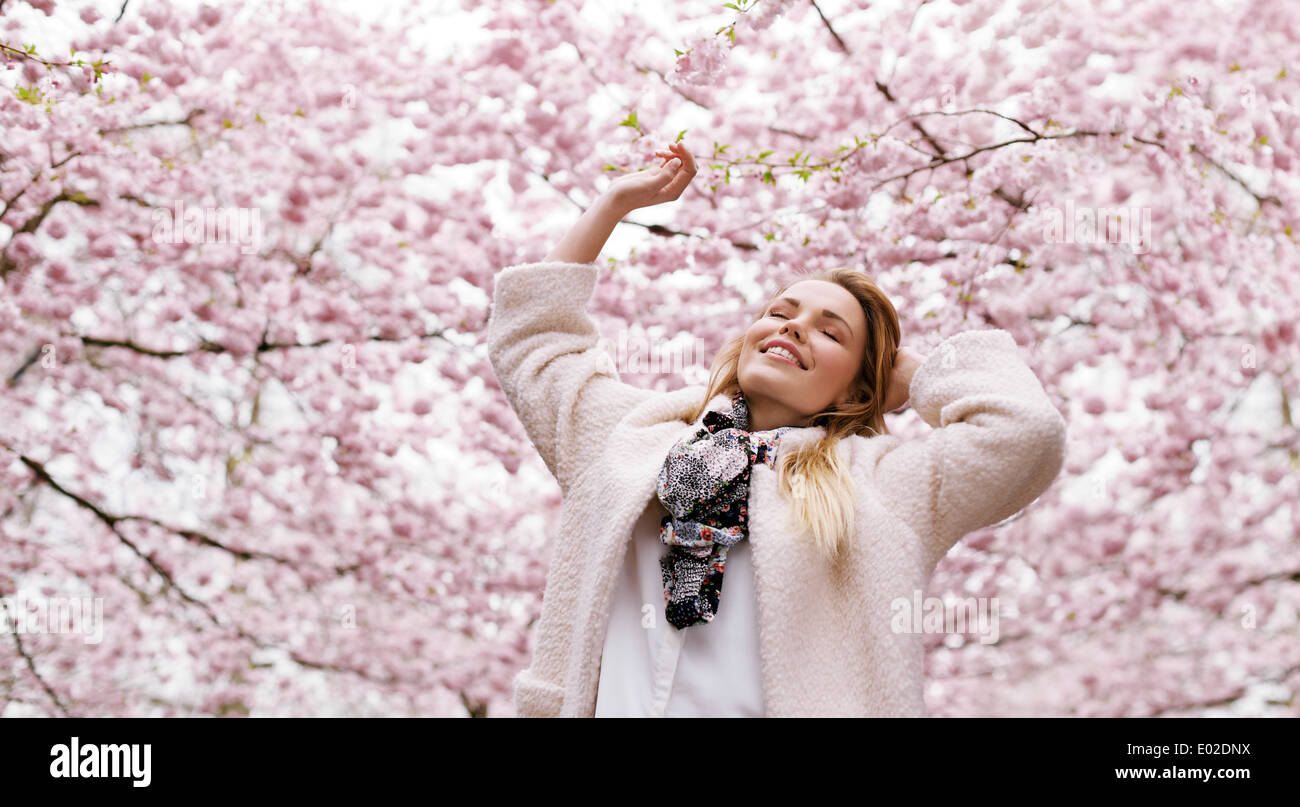 Happy young woman with her arms raised enjoying fresh air at spring ...