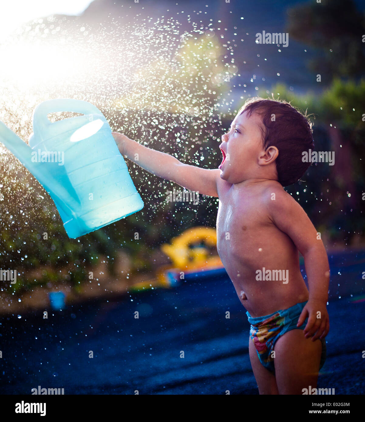Boy playing in a sprayer with a watering can hi-res stock photography ...