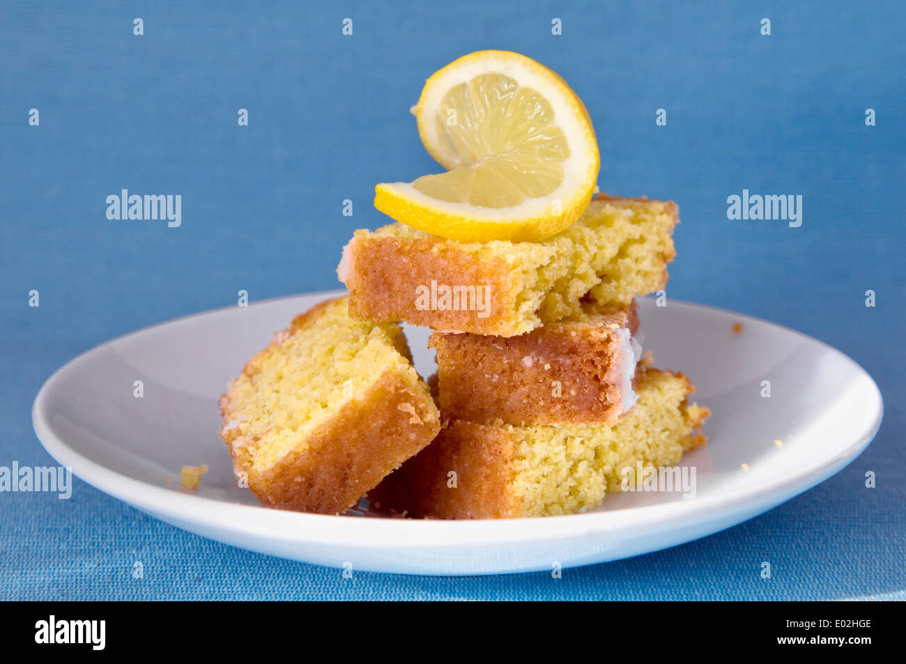Home made lemon cake slices on plate with slice of lemon on top against ...
