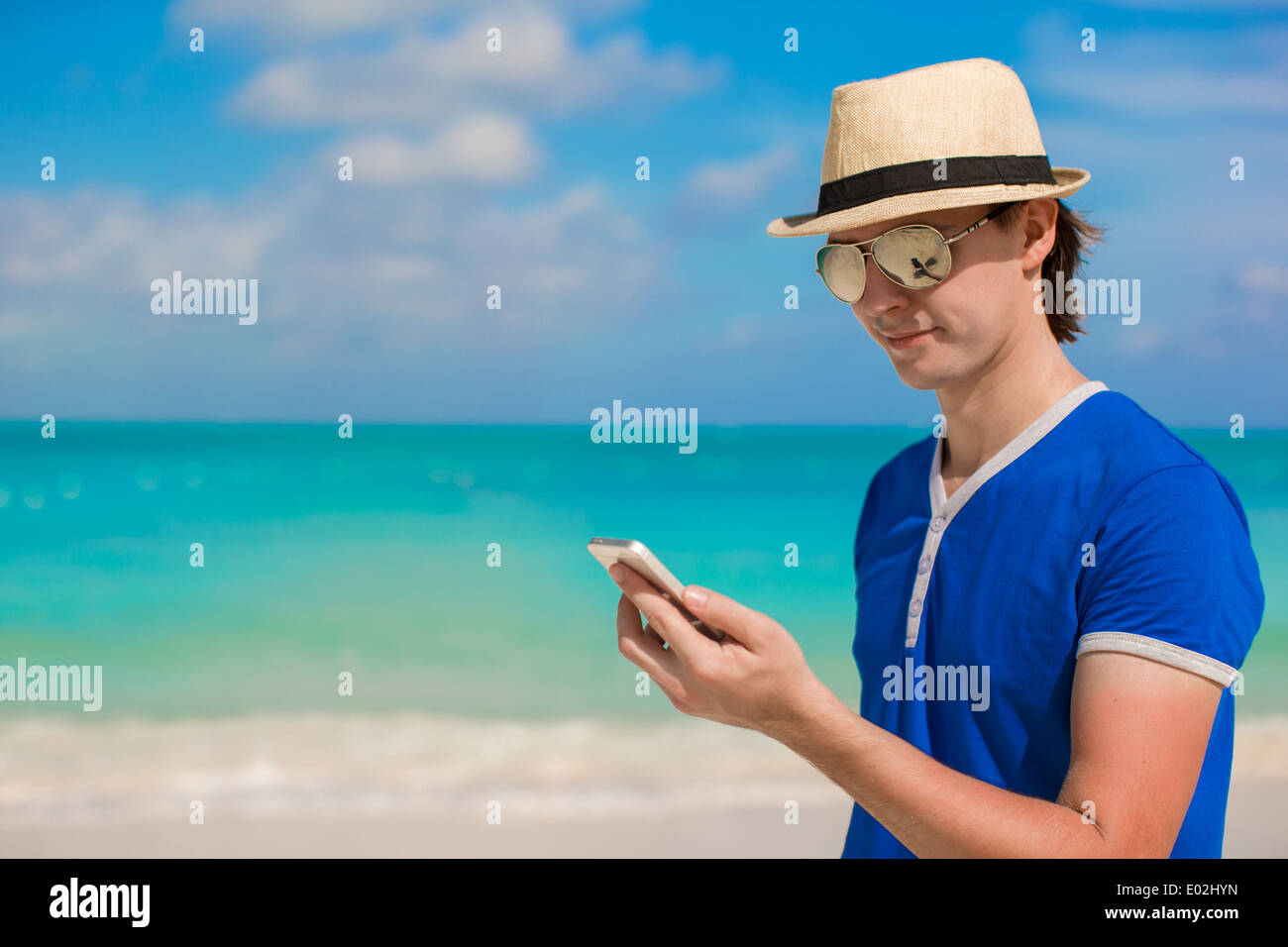 Young happy man with his phone on beach vacation Stock Photo - Alamy