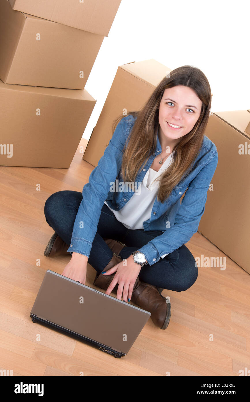 Beautiful girl with laptop and cardboard boxes unpacking in new home ...