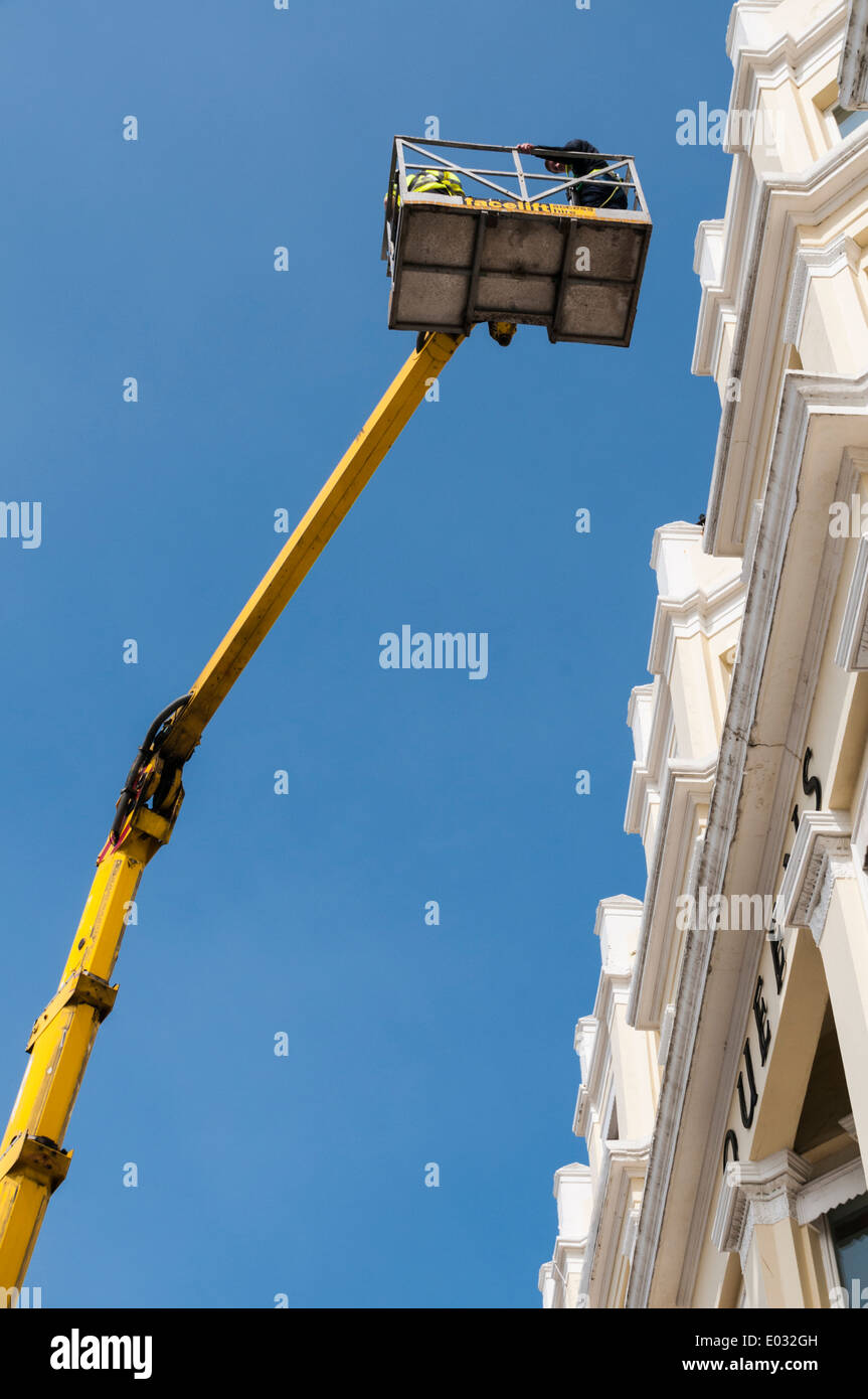Two workers being lifted inside a mechanical hoist to inspect the ...