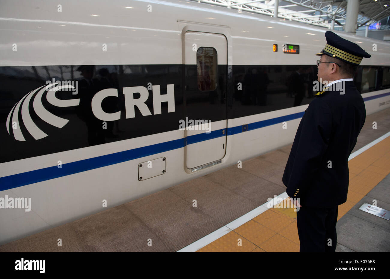 Train attendants stand on a platform as a high speed train arrives at ...