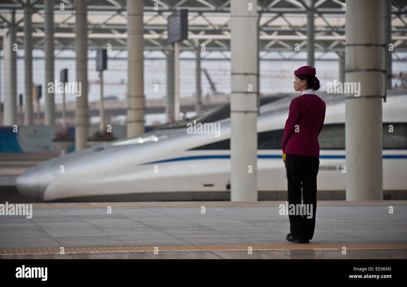 Train attendants stand on a platform as a high speed train arrives at ...