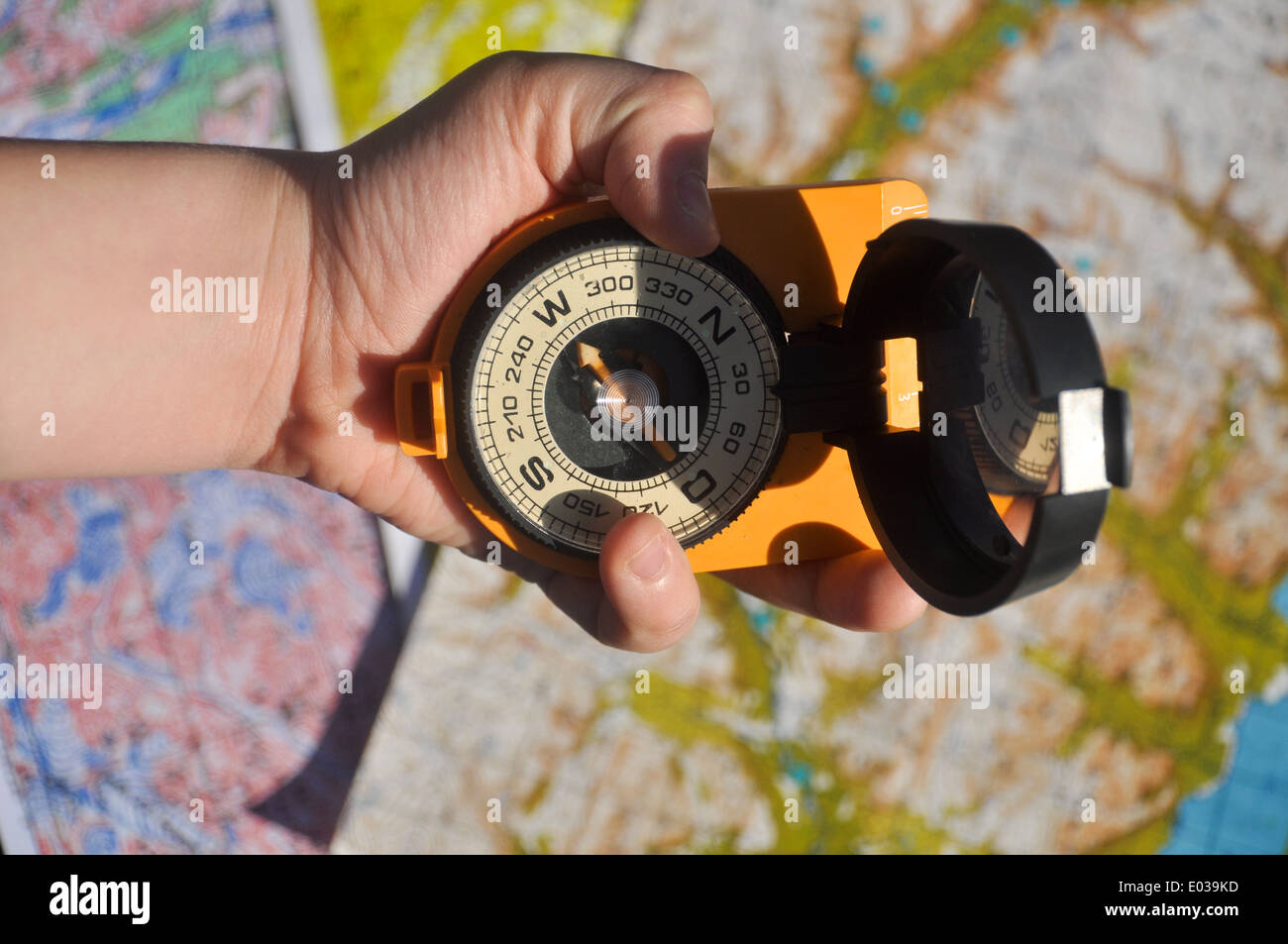 The compass in his hand under the bright sun on the background color ...