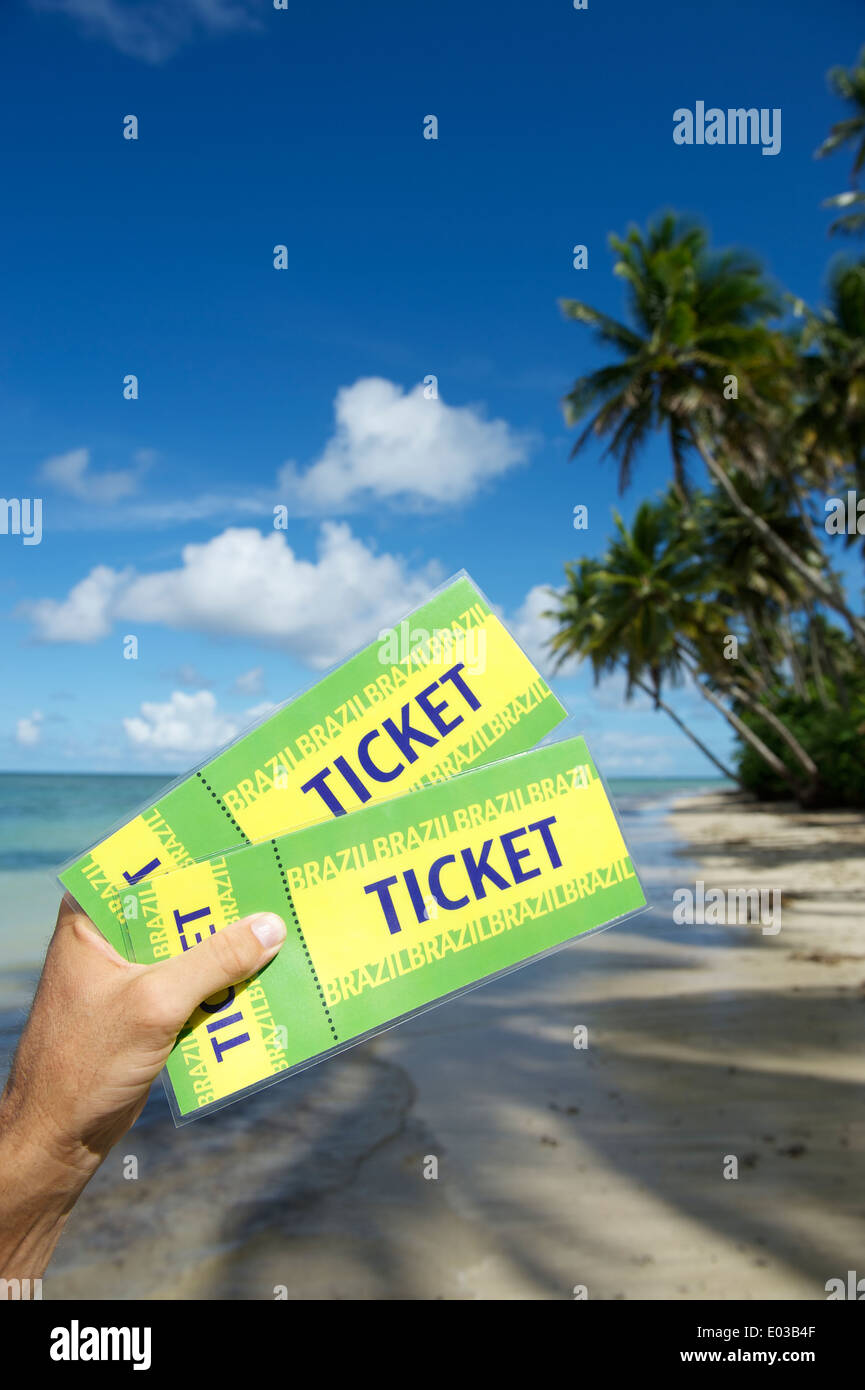 Hand holding pair of Brazil tickets in front of tropical palm trees ...