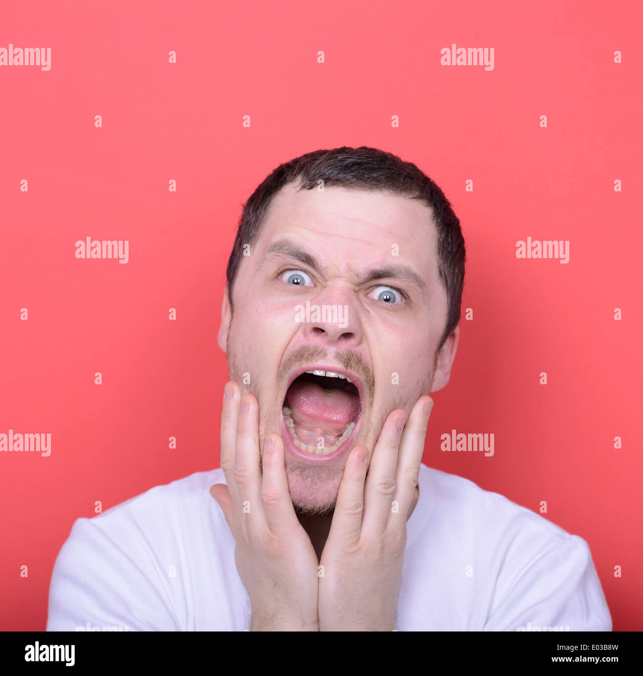 Portrait of angry man screaming against red background Stock Photo - Alamy