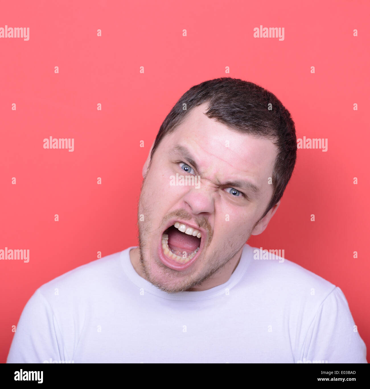 Portrait of angry man screaming against red background Stock Photo - Alamy