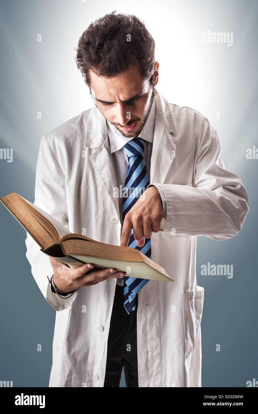 a young and handsome doctor or medical student reading an ancient book ...