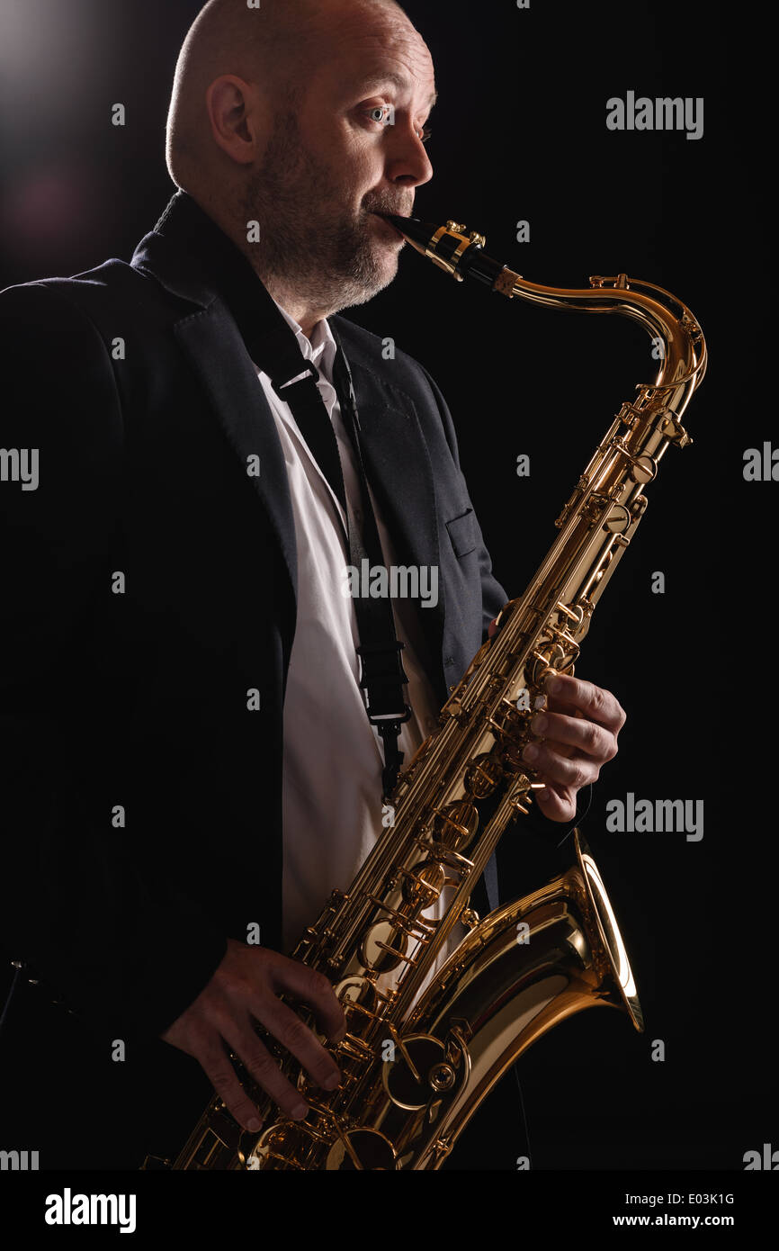 Adult musician playing tenor saxophone eyes open, dark background Stock ...