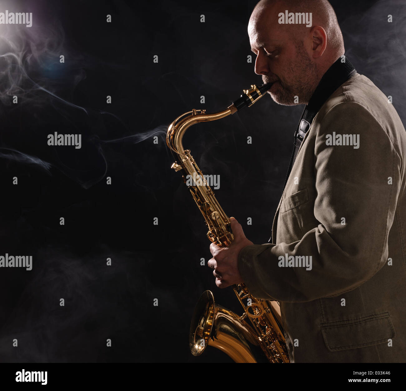 Adult musician playing tenor saxophone, profile view, smoky background ...