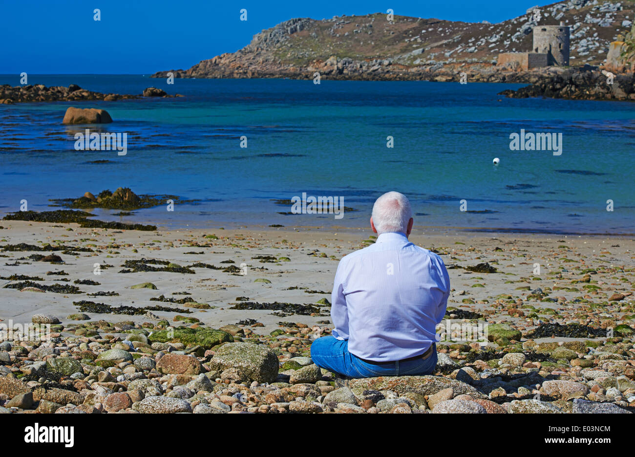man sitting on rocks and relaxing on beach at Bryher, Isles of Scilly ...