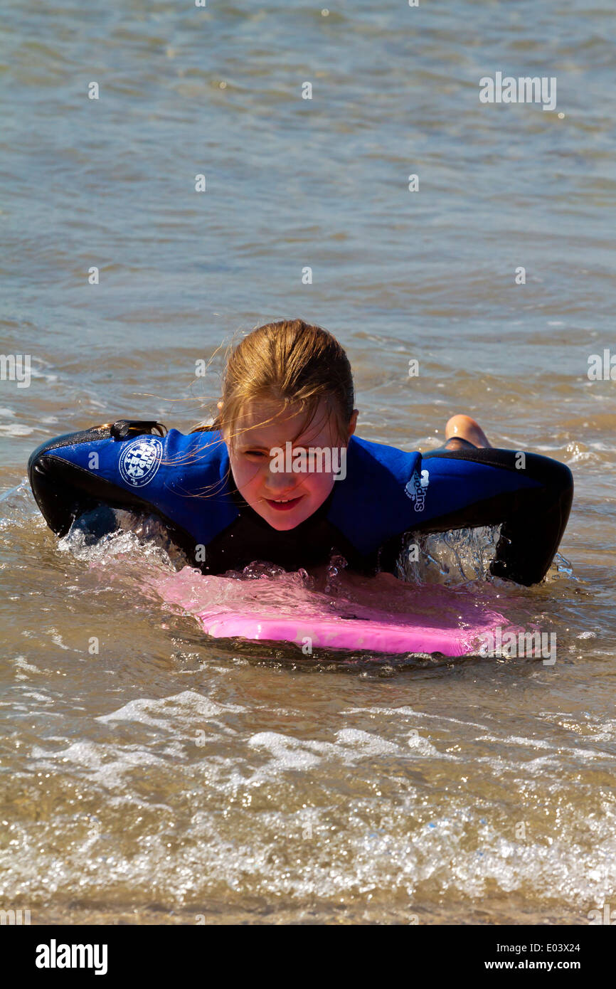 Eleven Year Old Girl Playing In Waves On Body Board On A Beach With