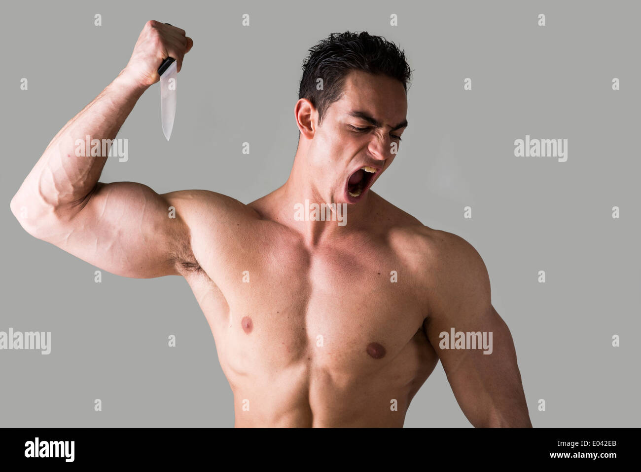 Muscular young man holding big knife ready to stab and screaming Stock ...