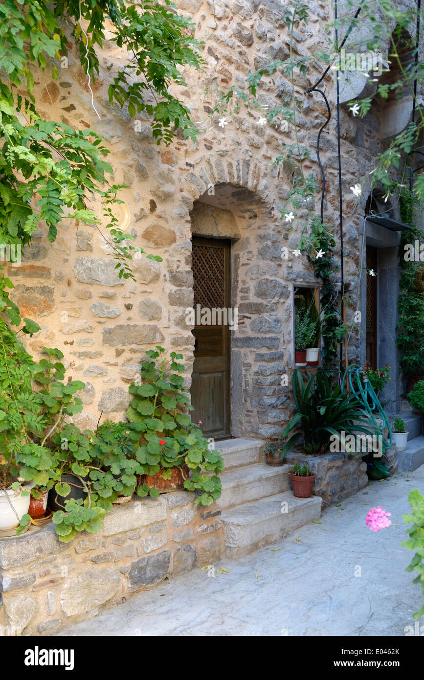 Plants drape stone house with stepped arched door in medieval town ...
