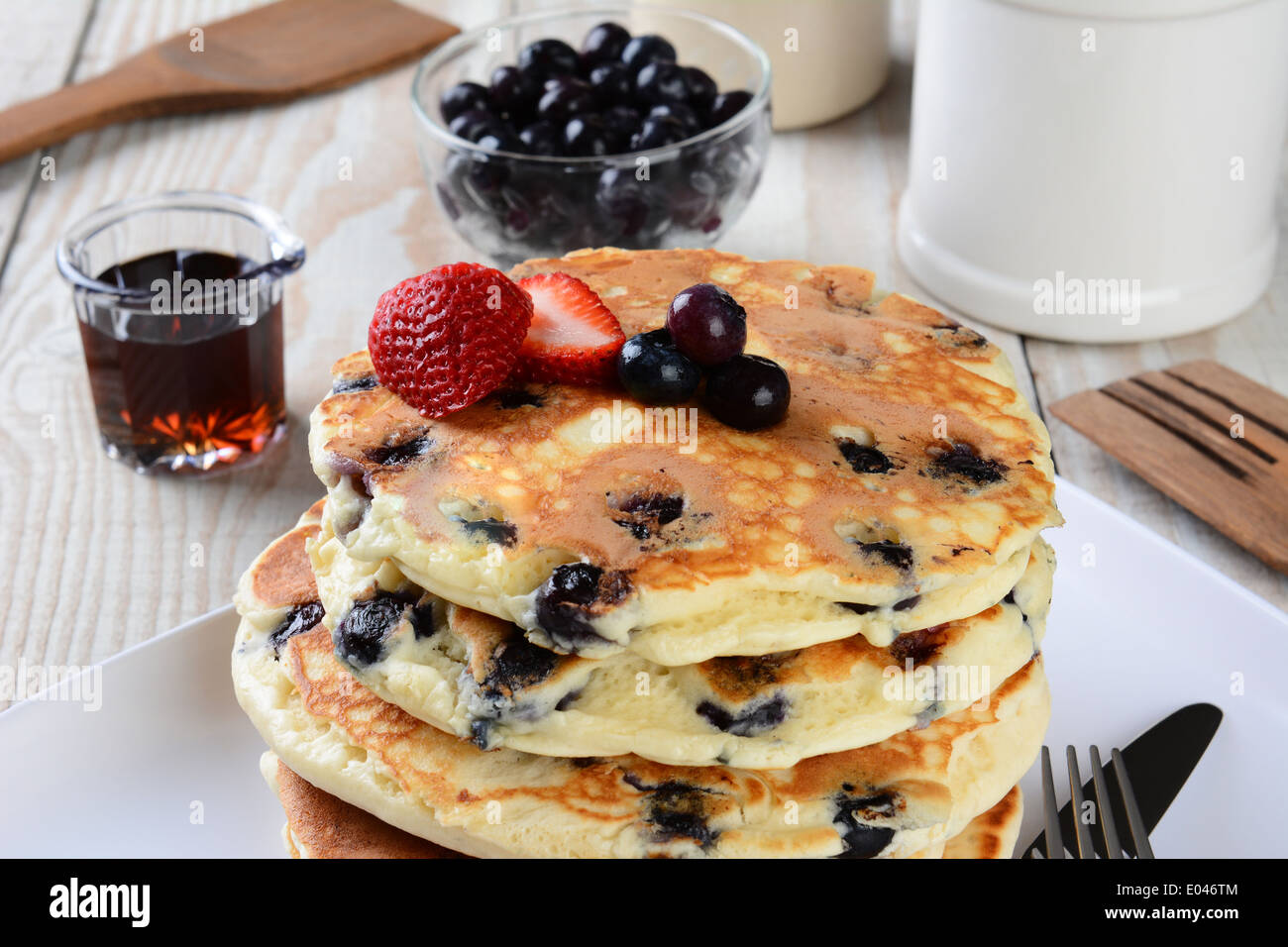 Blueberry Pancake Closeup with syrup pitcher, wooden spatula and fork ...