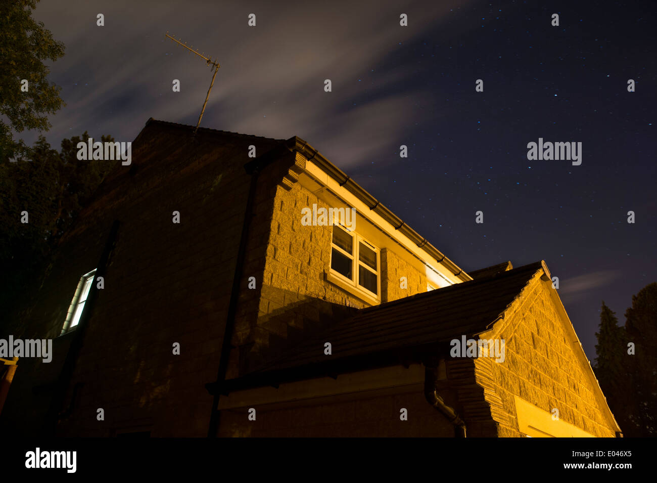 A dramatic nighttime partial view of a modern house exterior (lit by ...