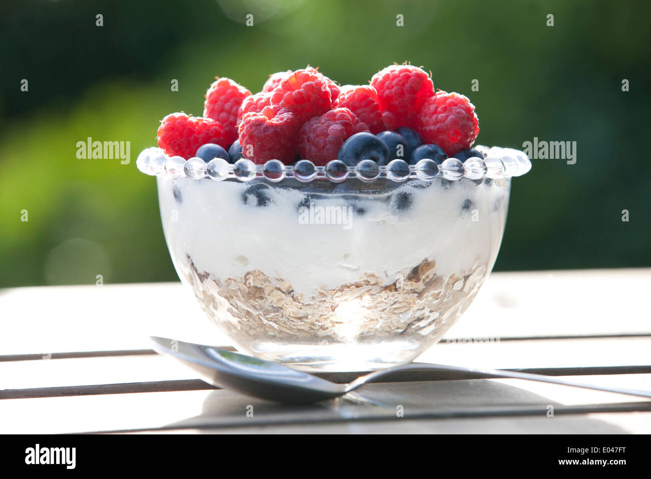 Granola, yoghurt, raspberries and blueberries in a glass dish with ...