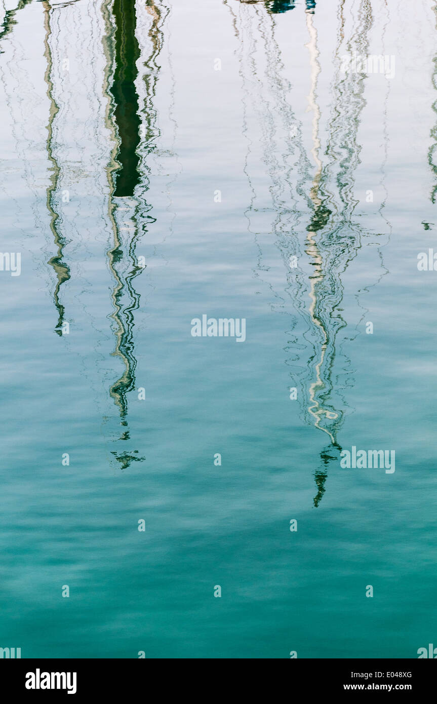Abstract image of boat mast reflections distorted by the gentle ripples ...