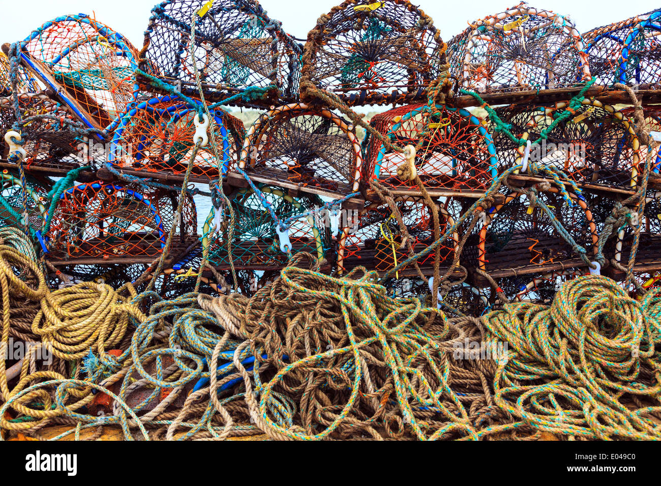 Collection of lobster pots and rope, stacked on a harbourside at ...