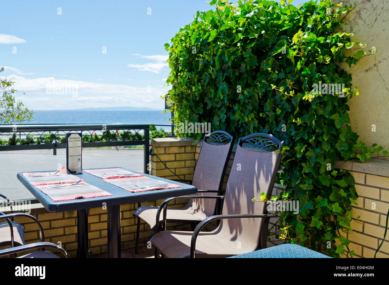 Empty outdoor patio table and chairs at a restaurant by the ocean. In ...