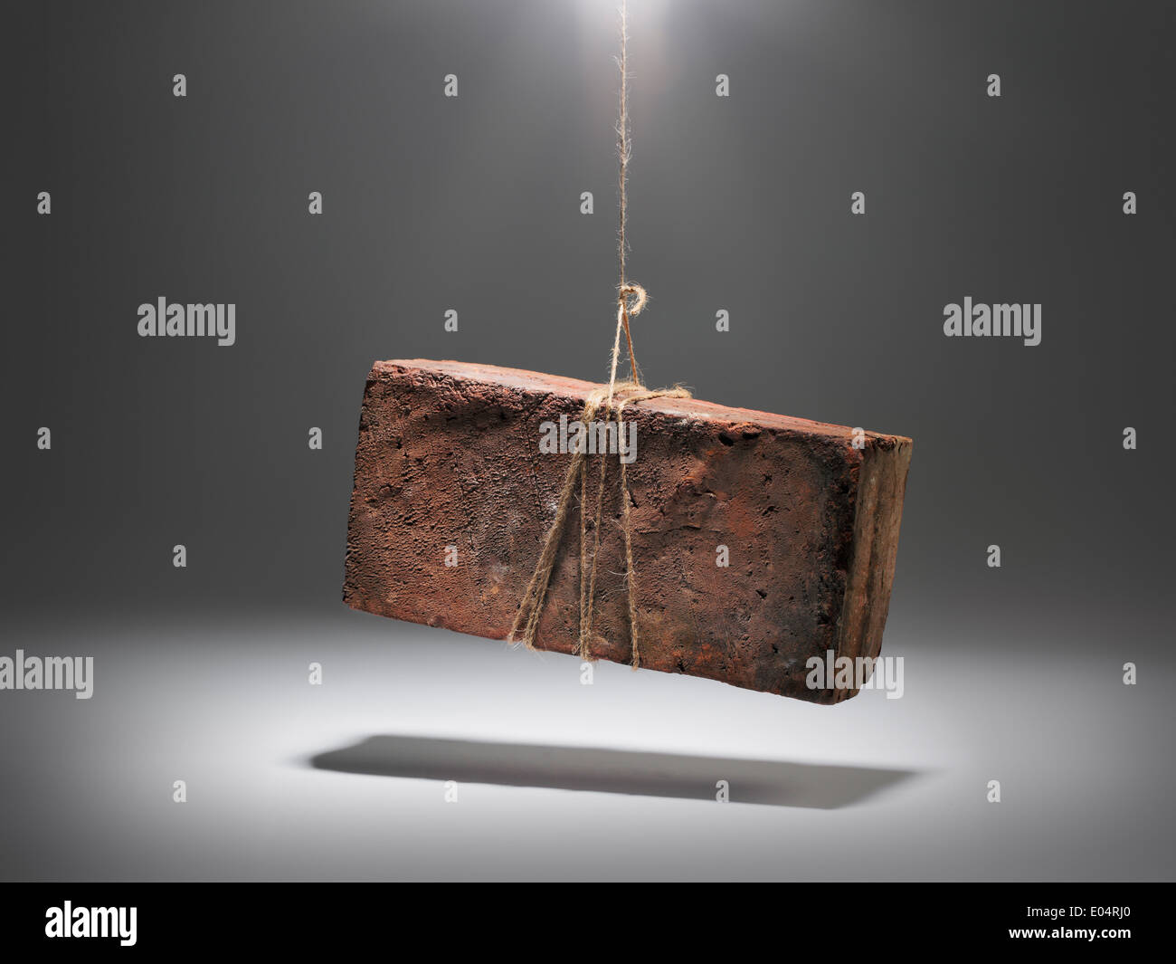 An old worn brick dangling from a string Stock Photo - Alamy