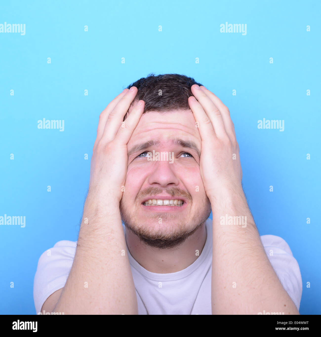 Portrait of sad man looking up against blue background Stock Photo - Alamy