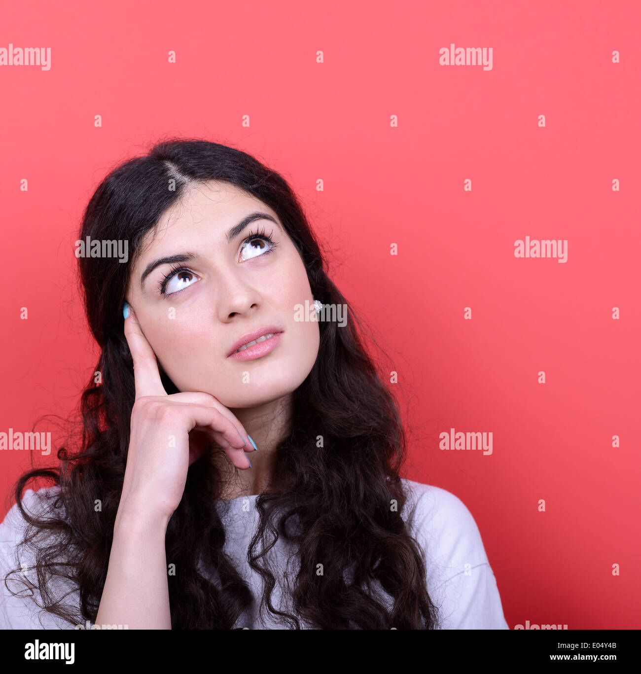 Portrait of beautiful girl thinking and looking up against red ...
