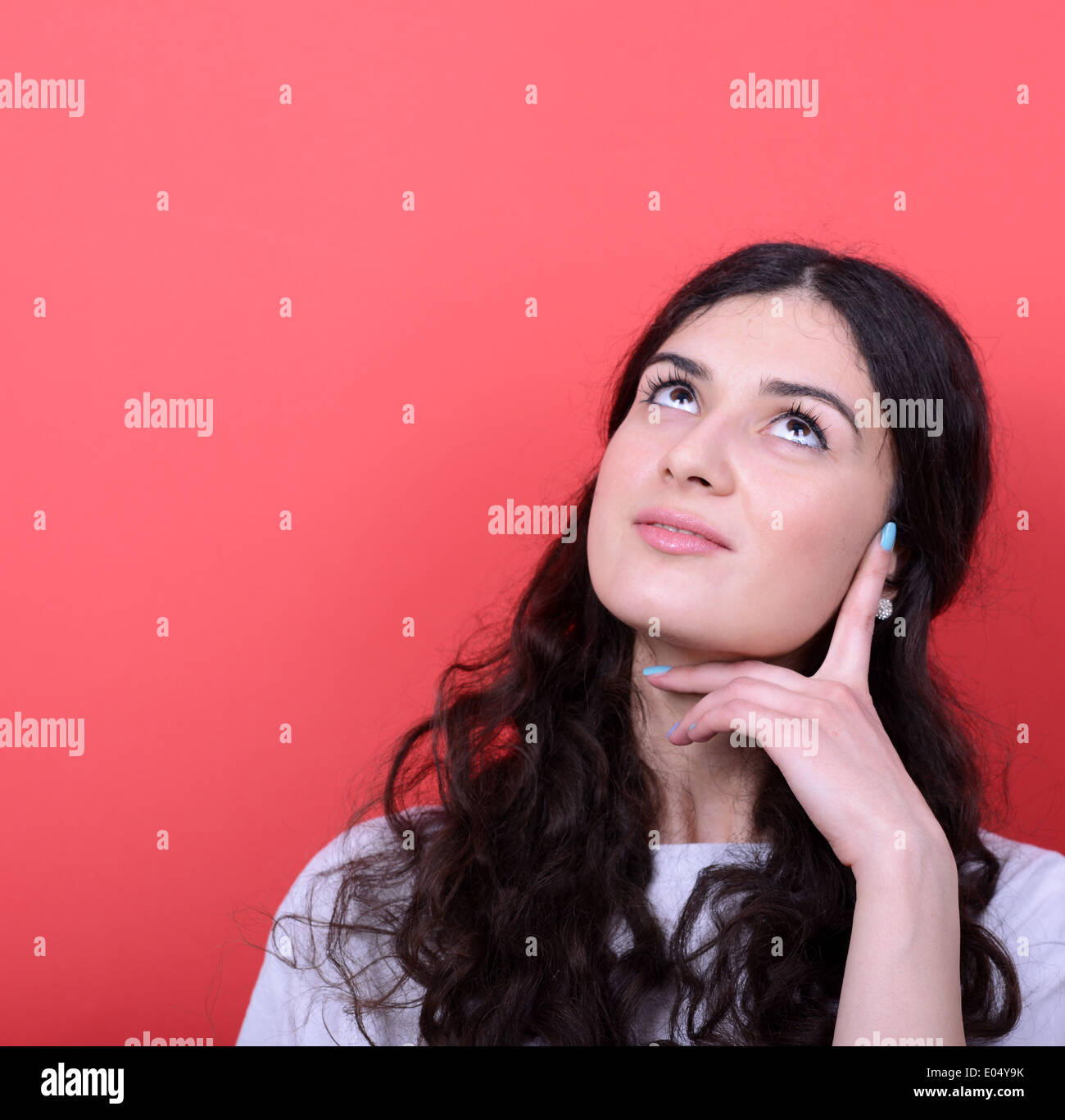 Portrait of beautiful girl thinking and looking up against red ...