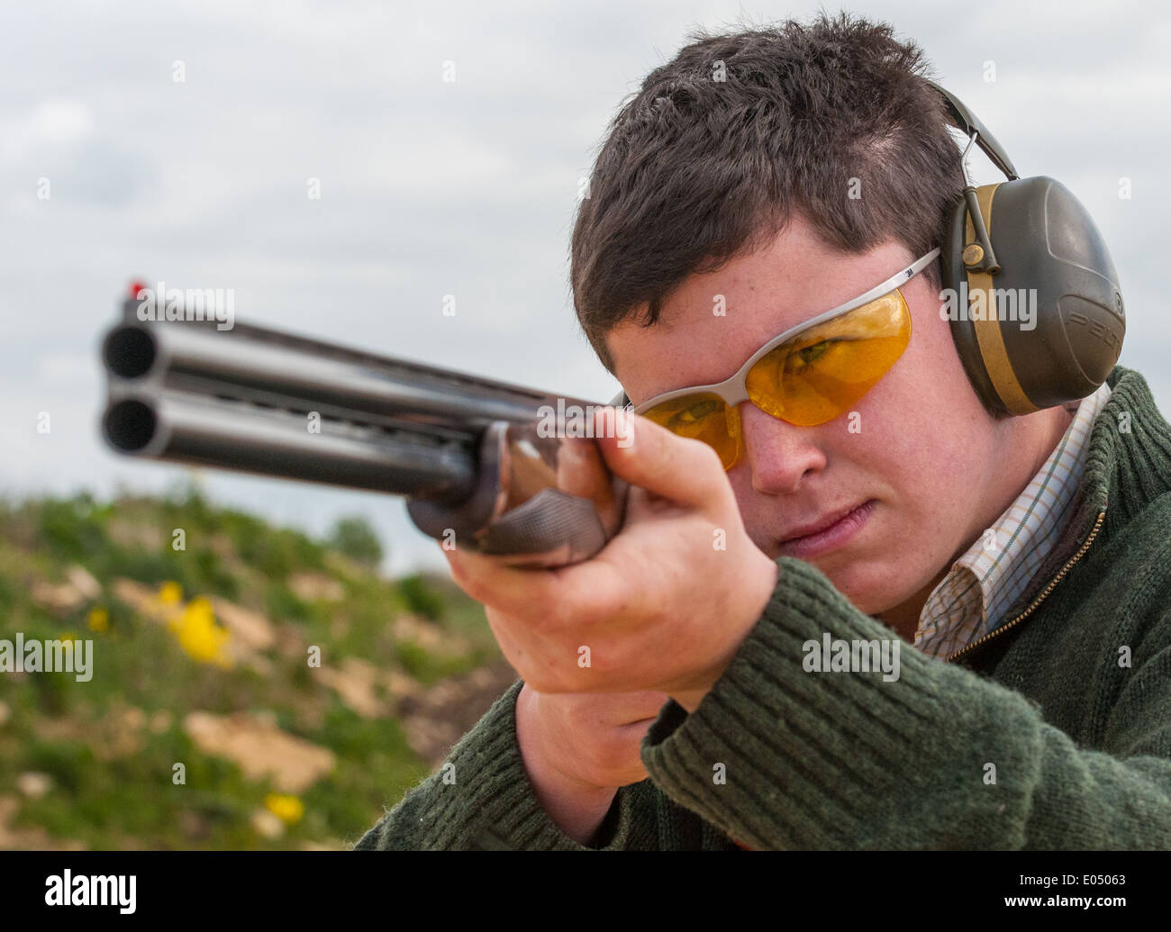 Young man with an over and under shot gun at a clay pigeon shooting ...