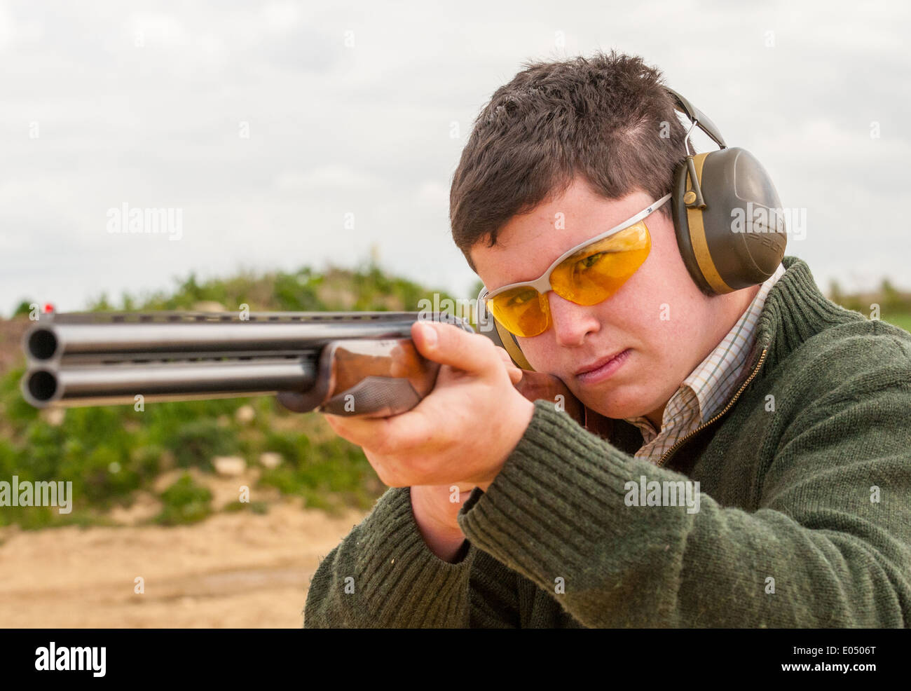Young man with an over and under shot gun at a clay pigeon shooting ...