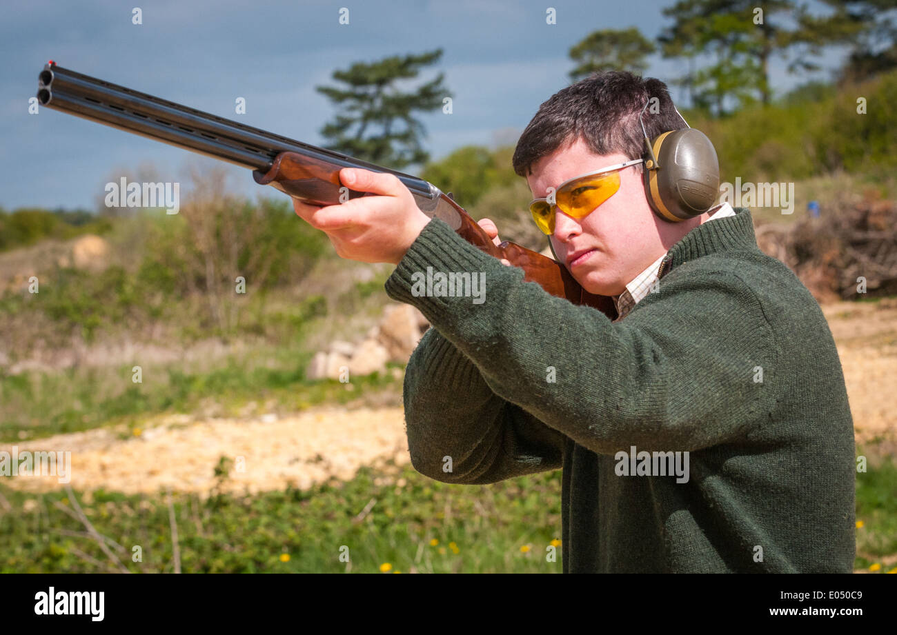 Young man with an over and under shot gun at a clay pigeon shooting ...