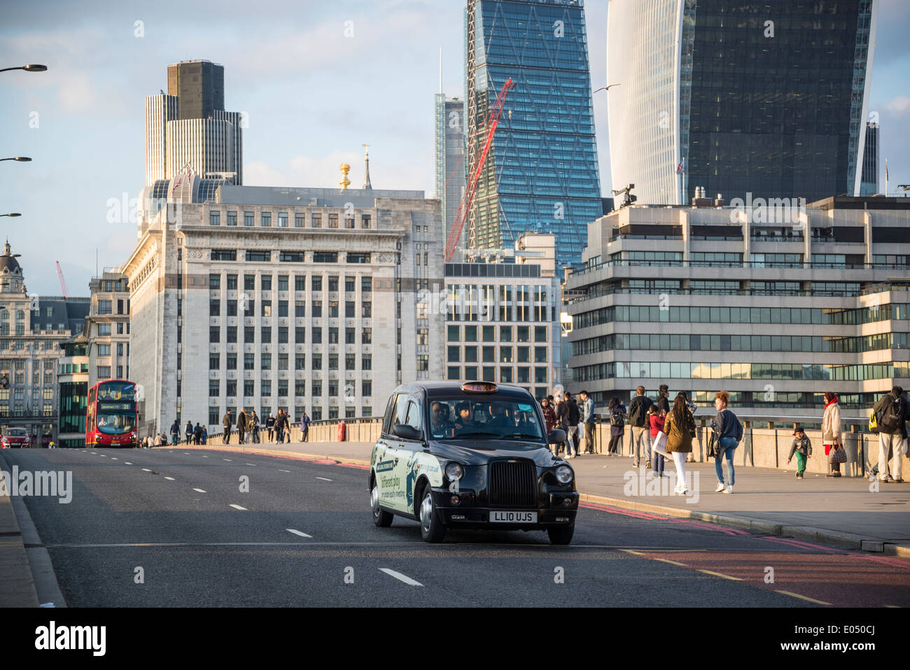 Taxi driving over London Bridge with the City buildings in the backdrop ...