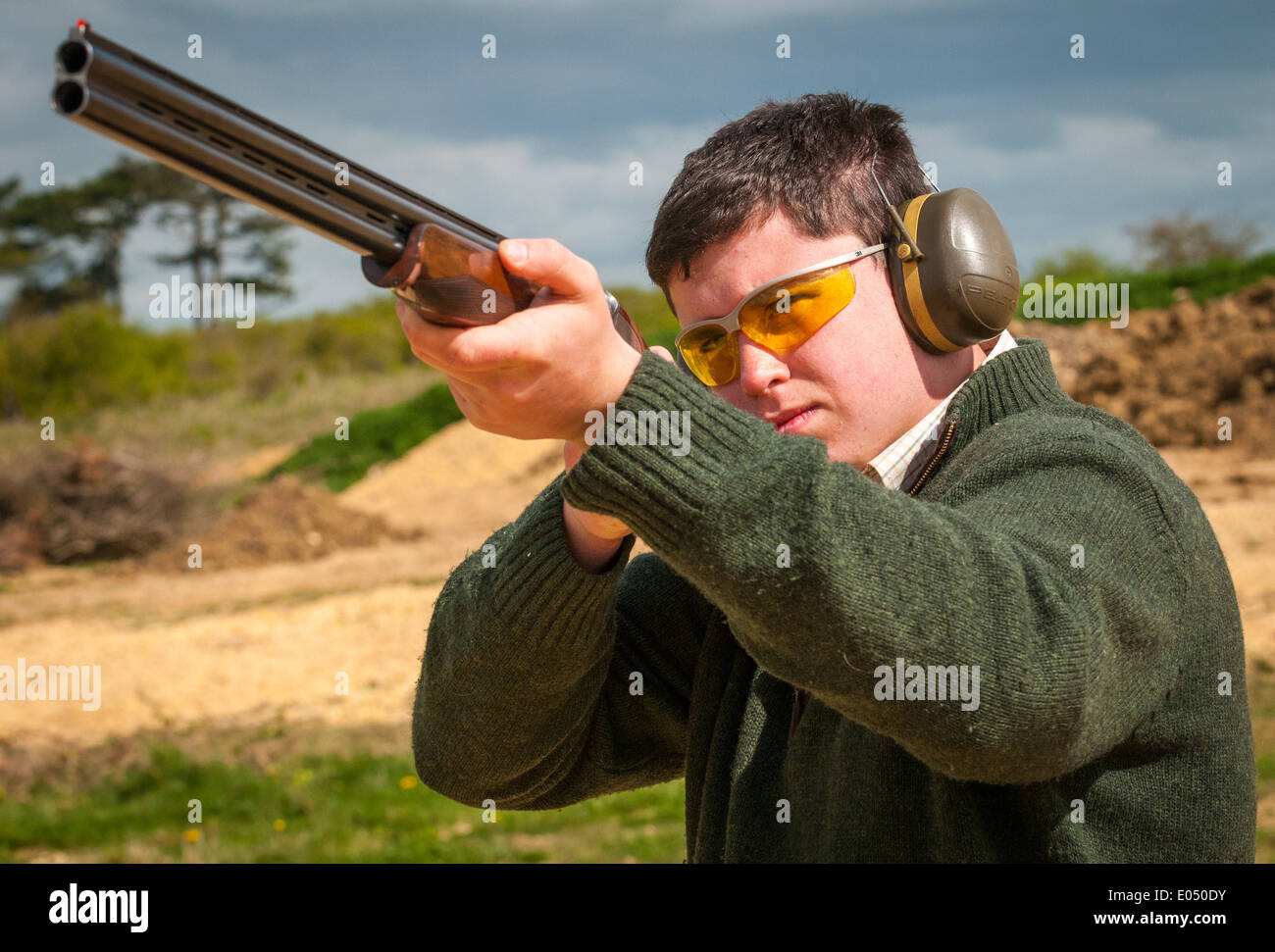 Young man with an over and under shot gun at a clay pigeon shooting ...