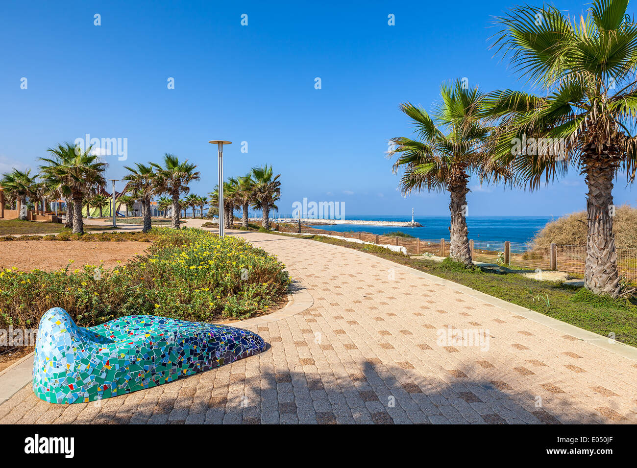 Paved promenade with palms and plants along shoreline of Mediterranean ...
