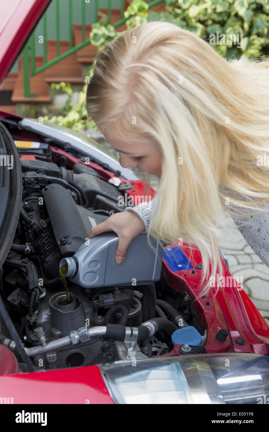 A young woman refills oil in her car. Sure journey with the right ...