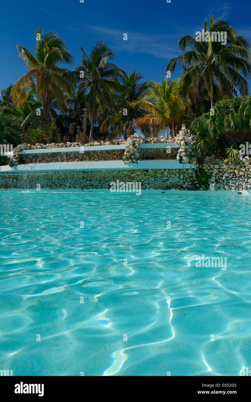 Palm trees and waterfall at large outdoor pool in vacation resort at ...