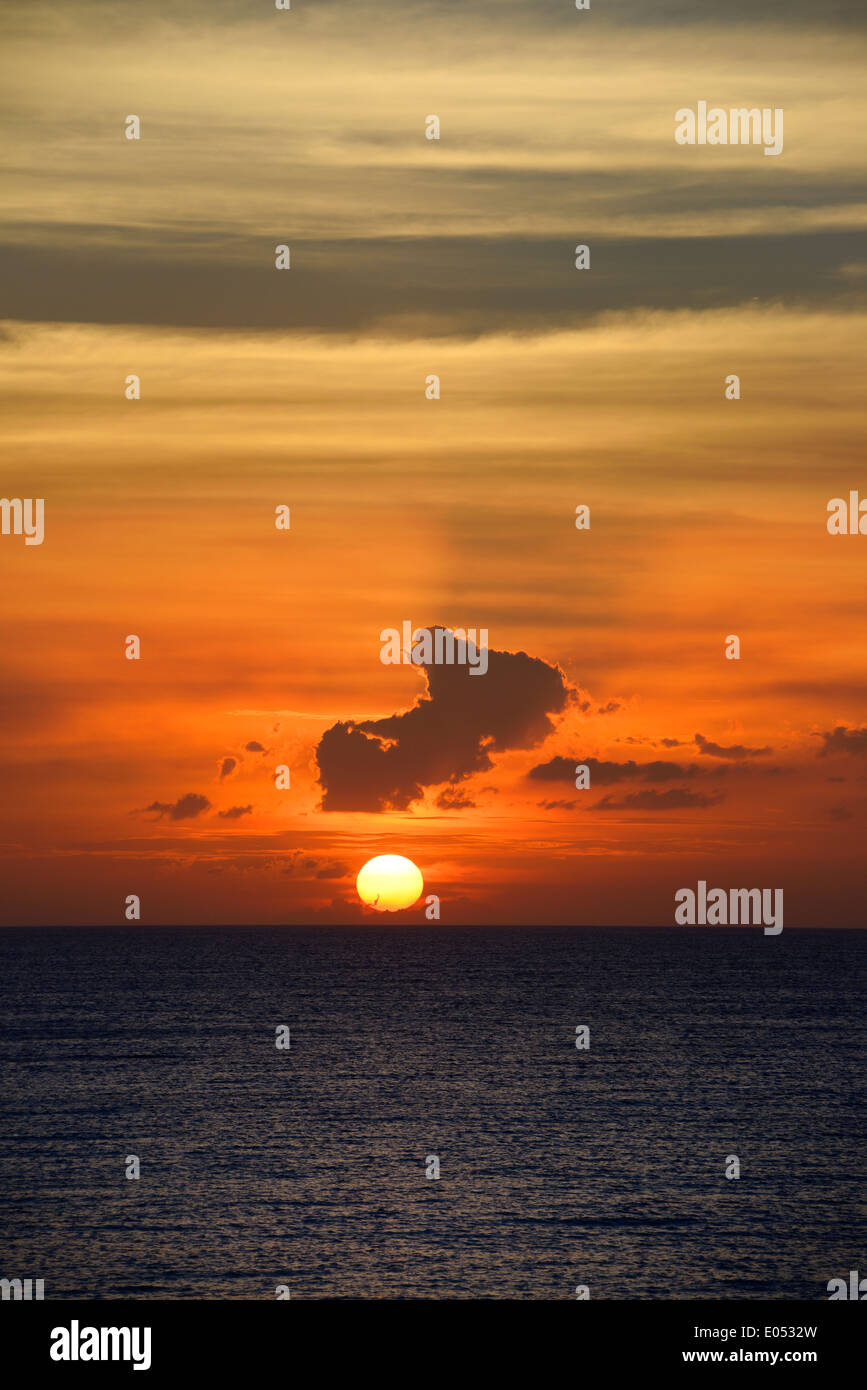 Orange ball sunset near horizon with clouds and sun rays over the ...