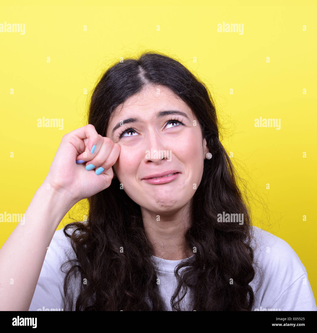 Portrait of woman crying and wiping tears against yellow background ...