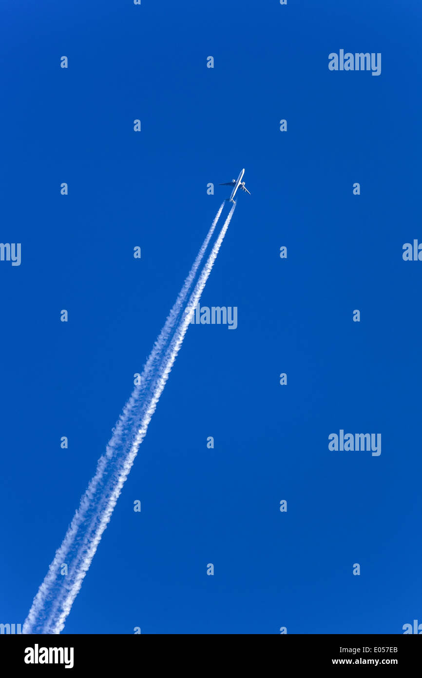 An airplane with condensation trail in the blue sky. Smog and air ...