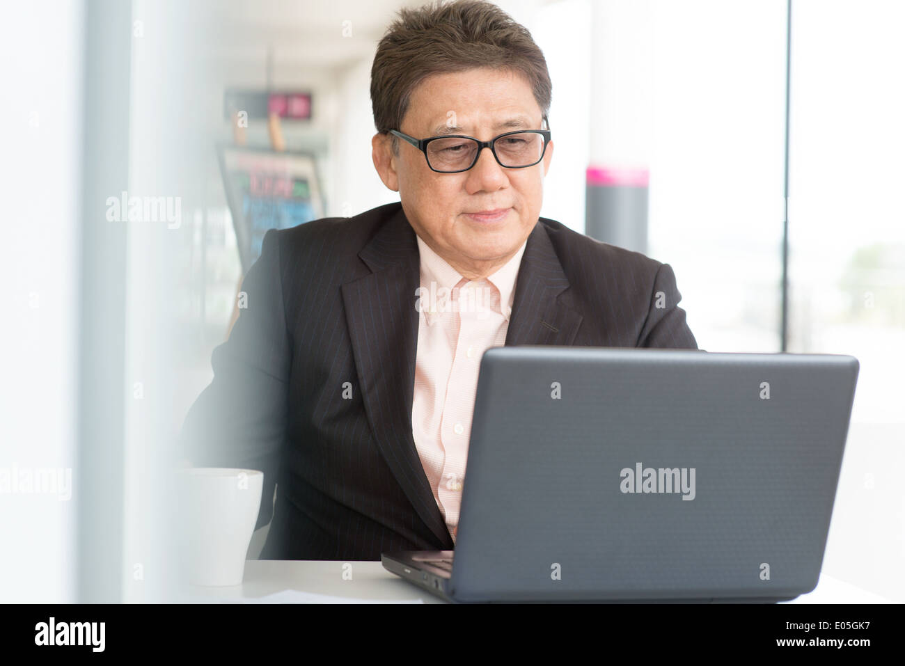 Asian Chinese CEO boss using internet with laptop at cafe. Senior male ...