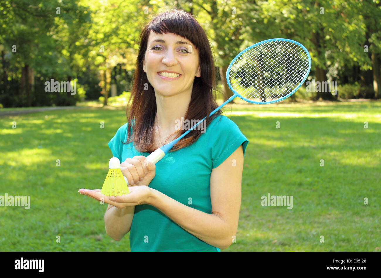 Smiling woman in the sunny park with badminton racket and badminton ...
