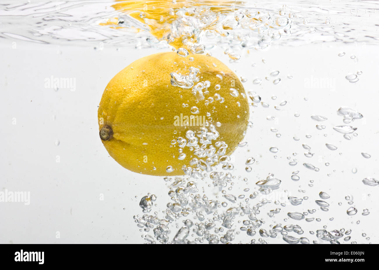 Bubbles forming in blue water after lemon is dropped into it Stock ...