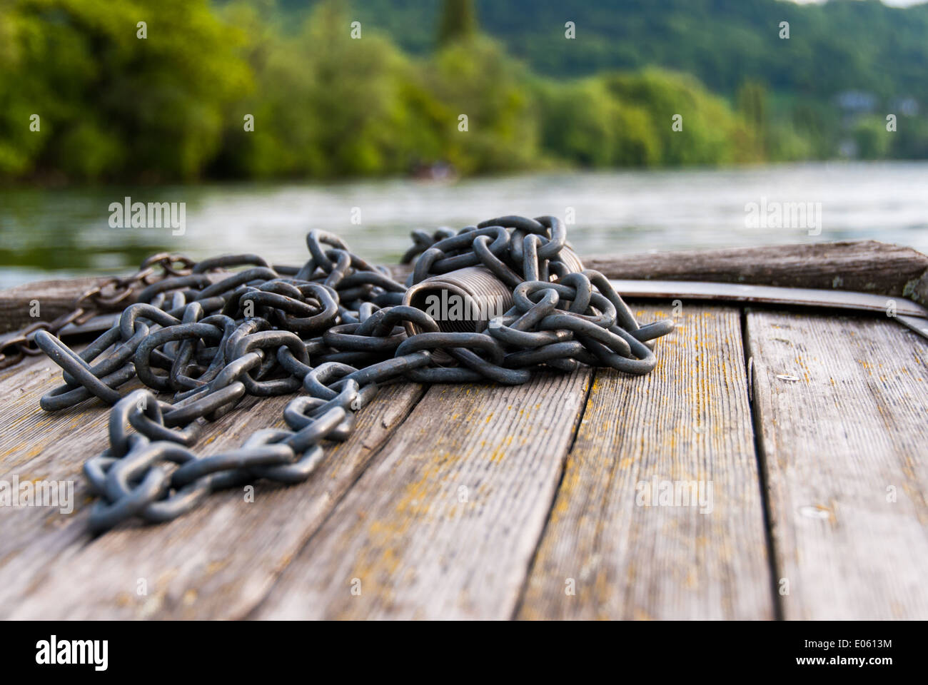 A close up of a chain on the planks of a boat navigating on the still ...